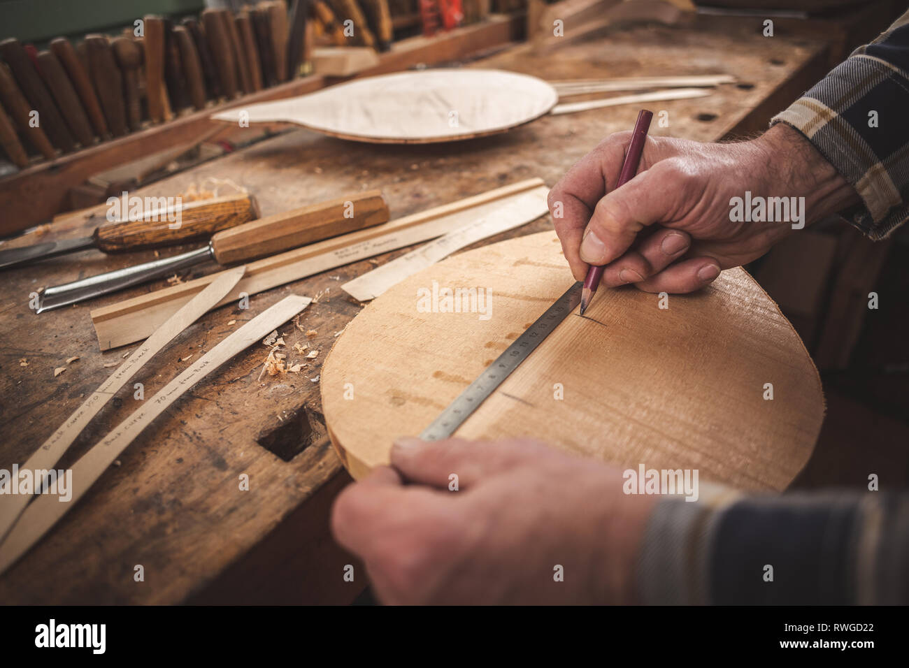 Hands of an instrument maker at a workbench measuring with a ruler and ...
