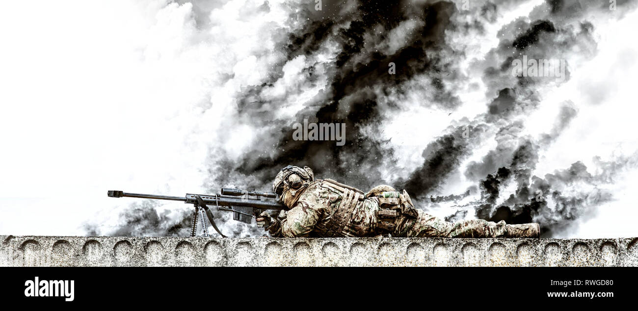 Sniper with large caliber rifle in action on the roof of a riuned ...