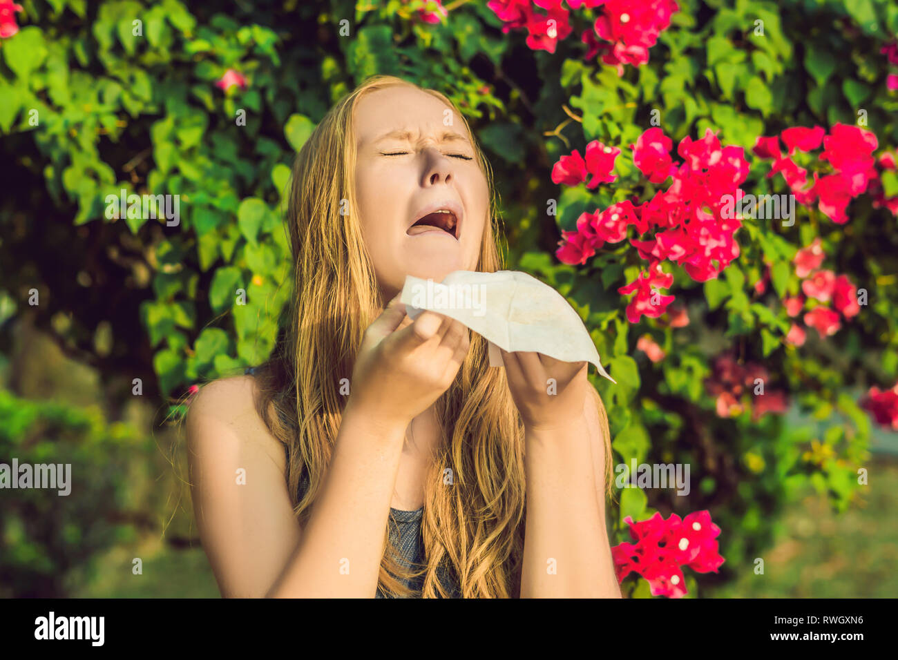 Young pretty woman blowing nose in front of blooming tree. Spring allergy concept Stock Photo ...