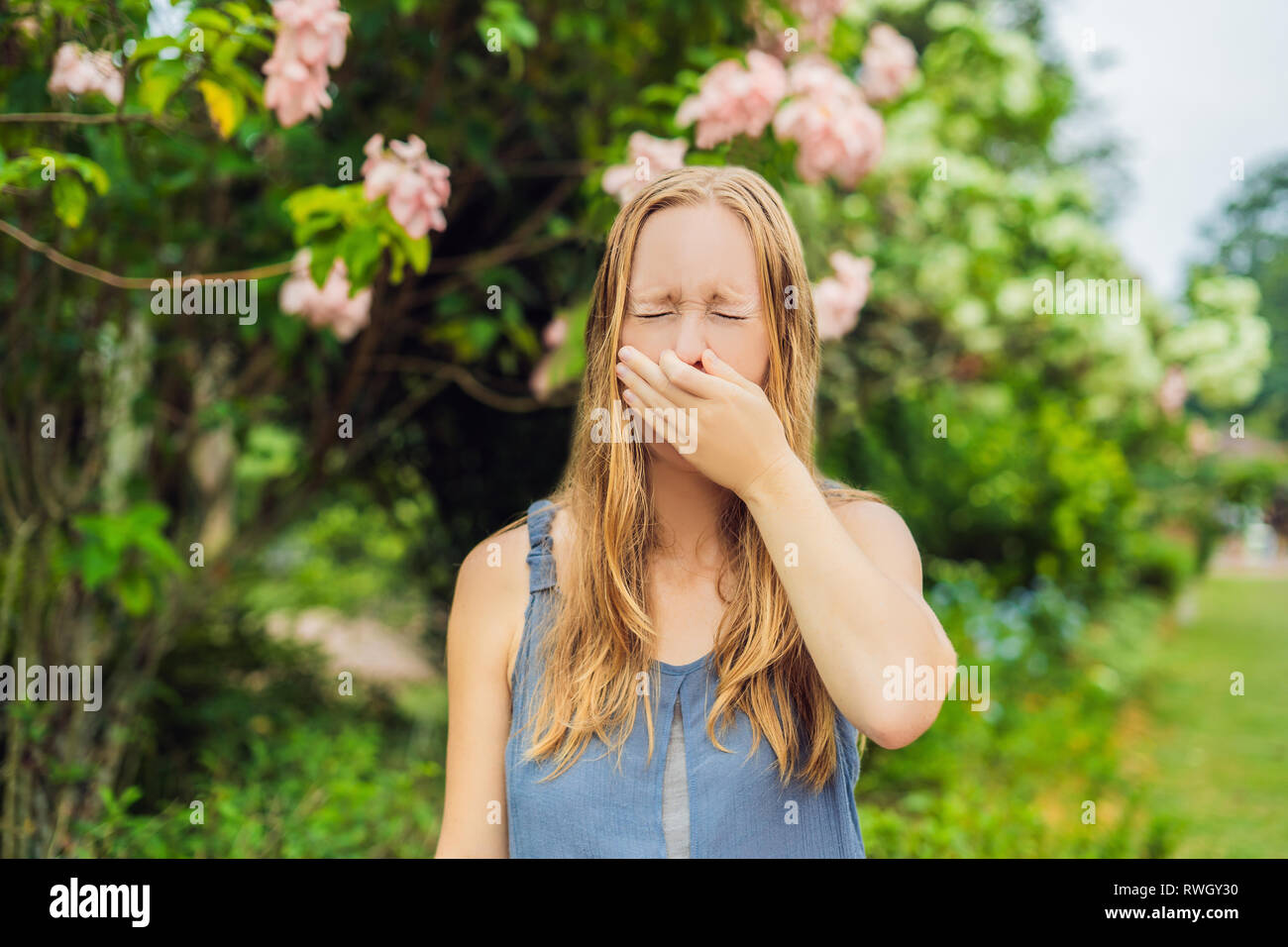 Young pretty woman blowing nose in front of blooming tree. Spring allergy concept Stock Photo ...