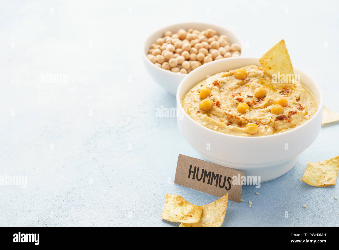 Hummus dip served with chickpeas, chips and paprika. Blue background ...