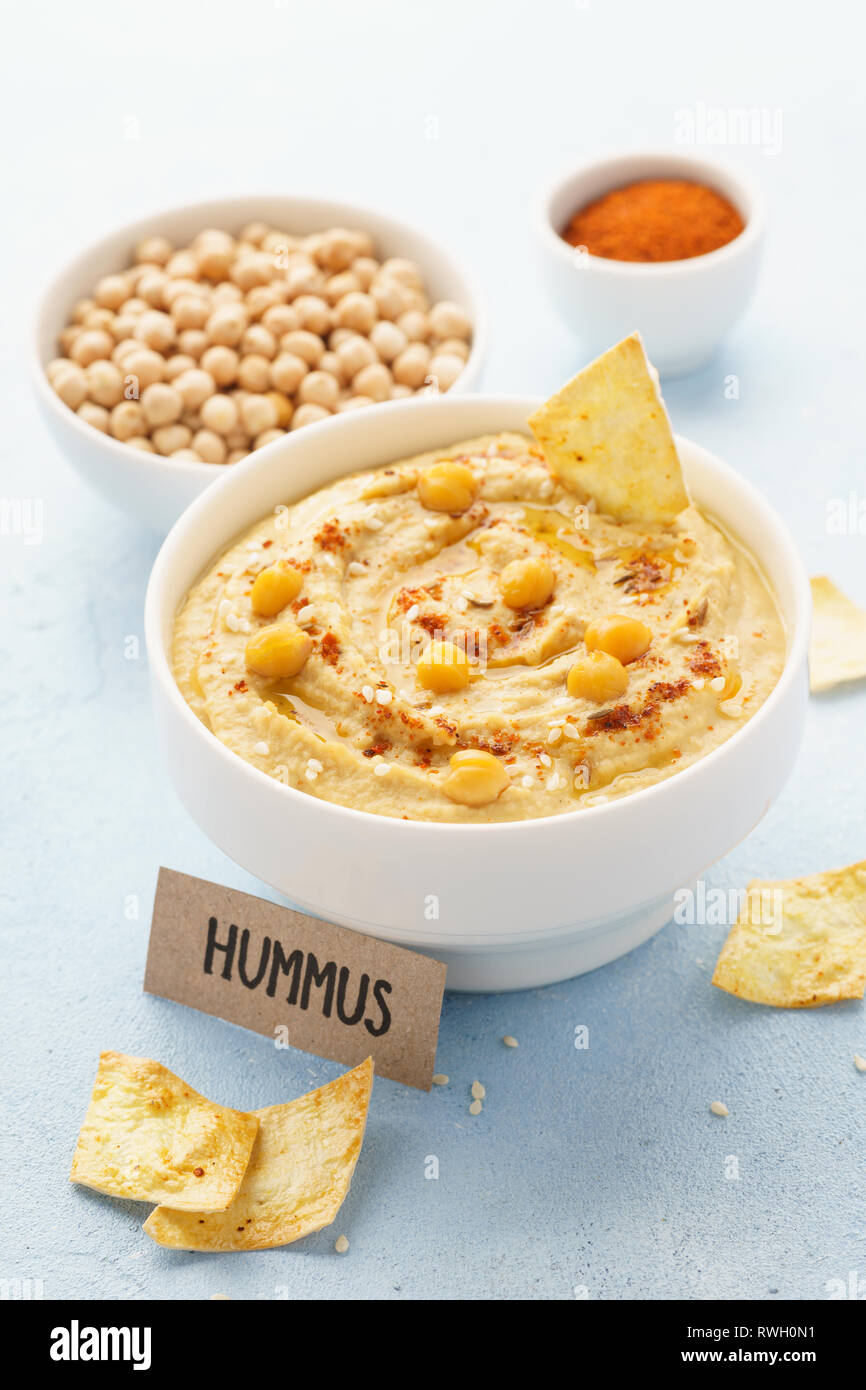 Hummus dip served with chickpeas, chips and paprika. Blue background ...