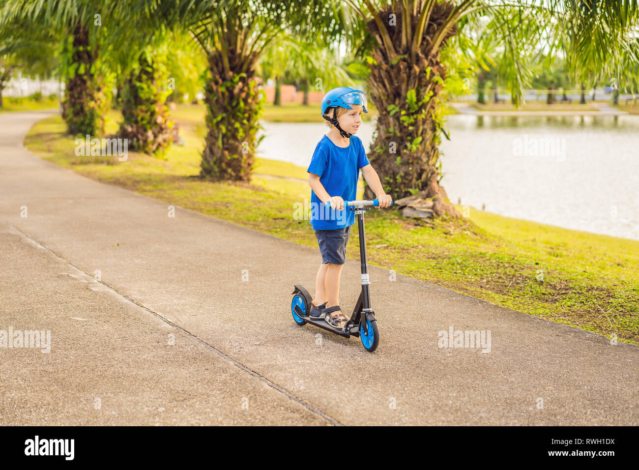 Boy riding scooters, outdoor in the park, summertime. Kids are happy ...