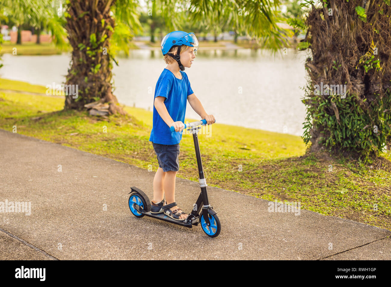 Boy riding scooters, outdoor in the park, summertime. Kids are happy ...