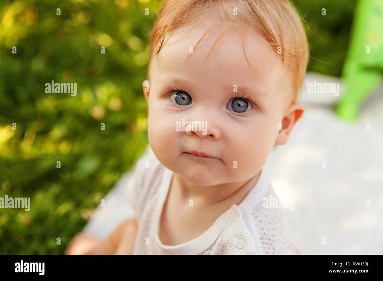 Sweet happy little baby girl sitting on grass in park, garden, meadow ...