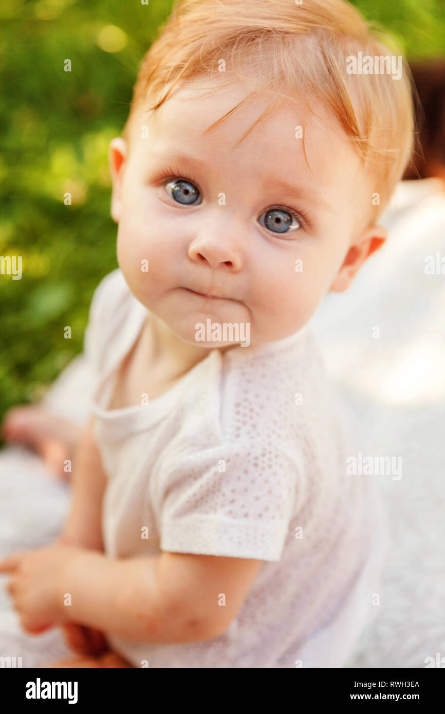 Sweet happy little baby girl sitting on grass in park, garden, meadow ...