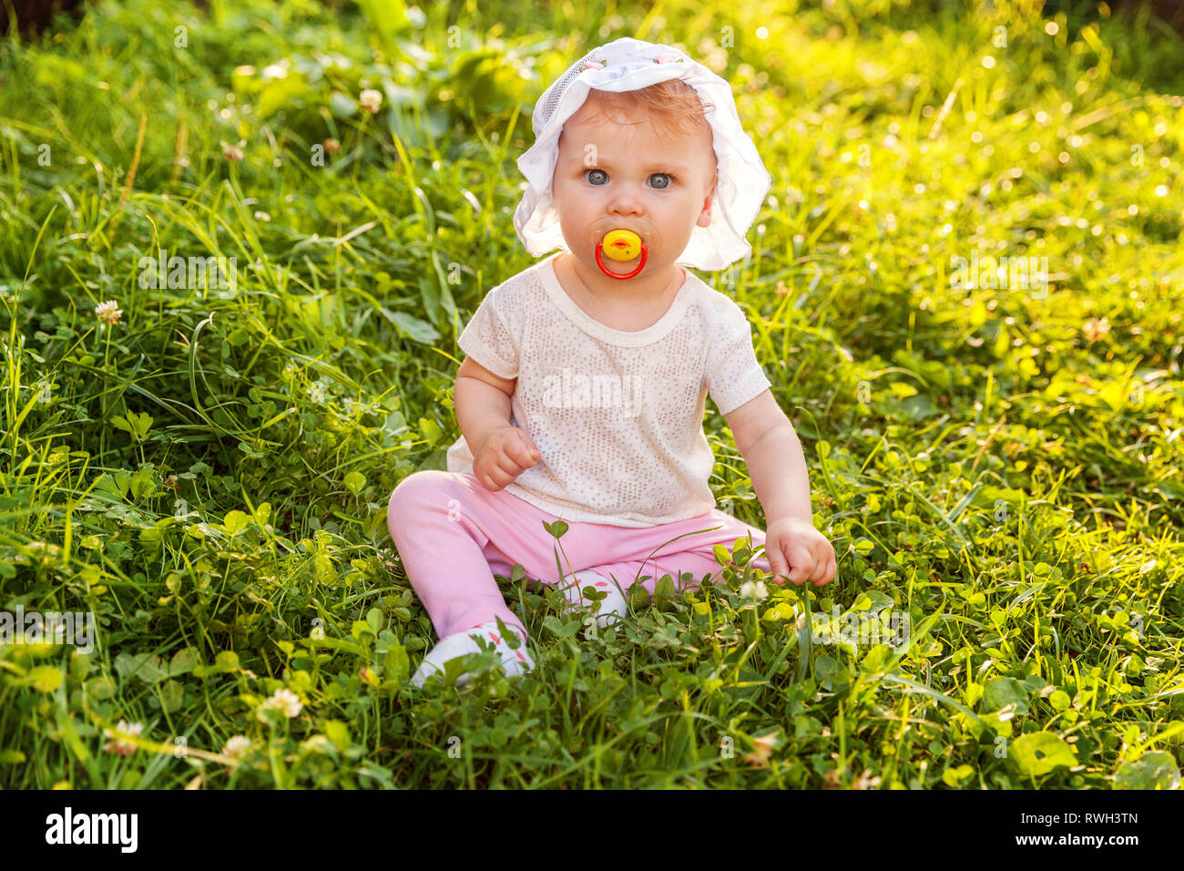 Sweet happy little baby girl sitting on grass in park, garden, meadow ...