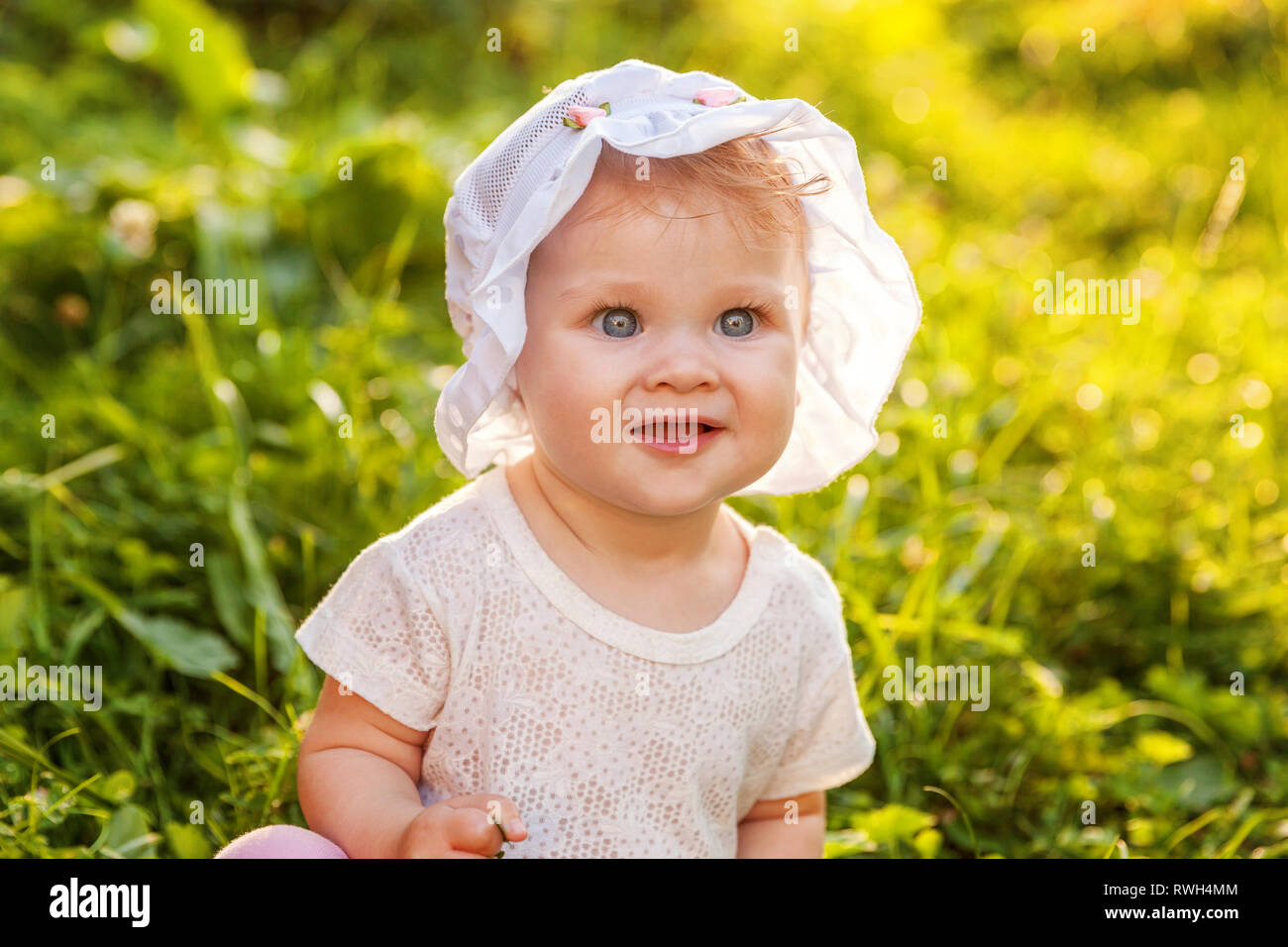 Sweet happy little baby girl sitting on grass in park, garden, meadow ...
