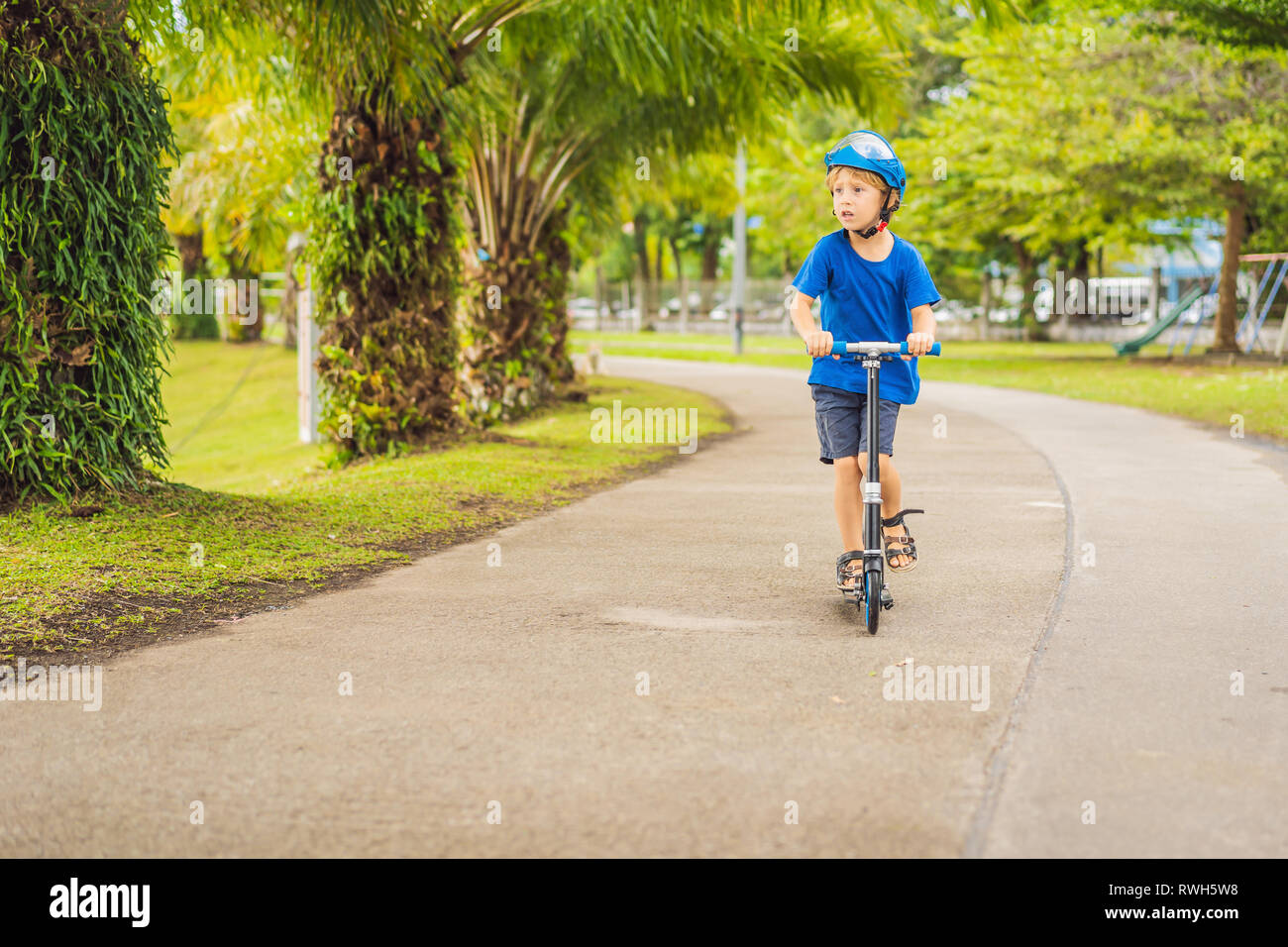 Boy riding scooters, outdoor in the park, summertime. Kids are happy ...