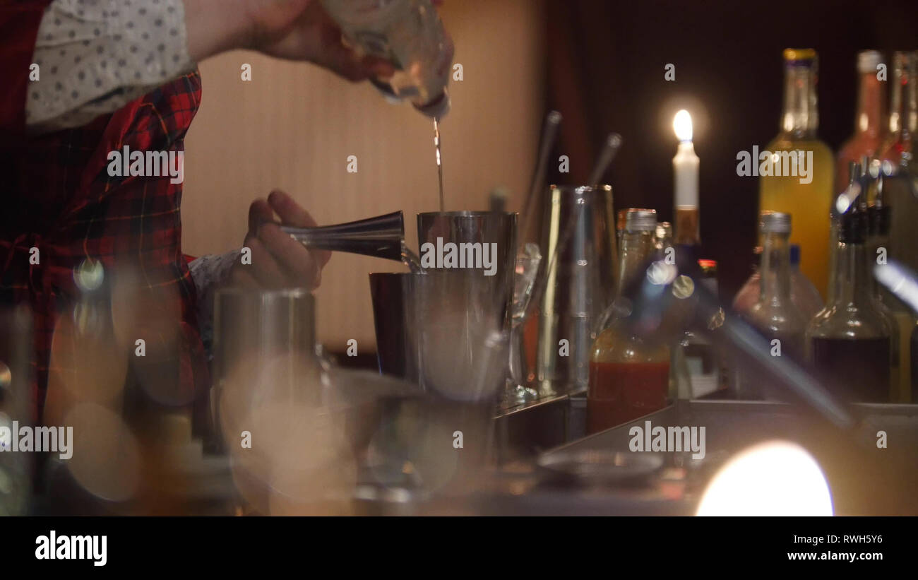 Young professional bartender pouring vodka and mixing vodka in the ...