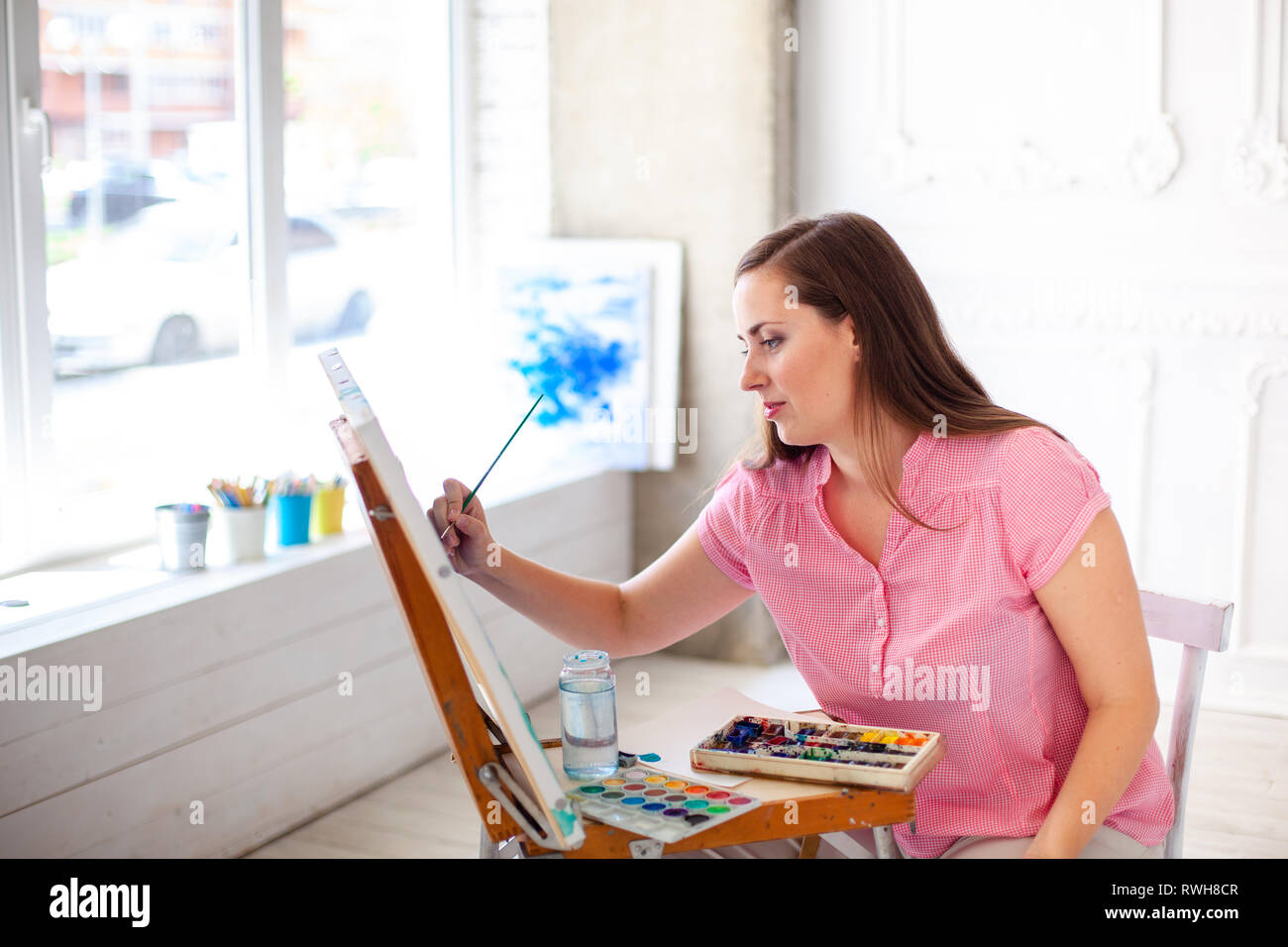 Pretty talented female painter painting on easel, making colorful ...