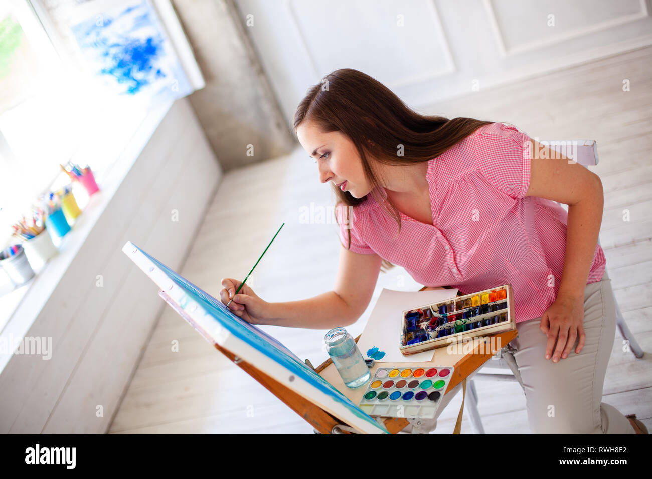 Portrait of a gorgeous female artist working on several art projects on ...