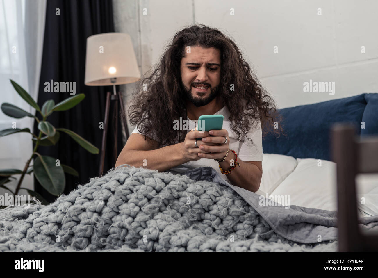 Sad stressed man looking at his smartphone screen Stock Photo - Alamy