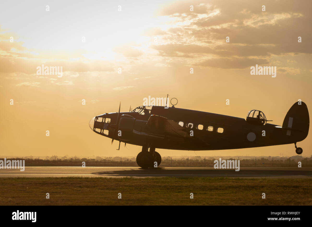 Lockheed Hudson WWII light bomber landing against an orange sunset ...