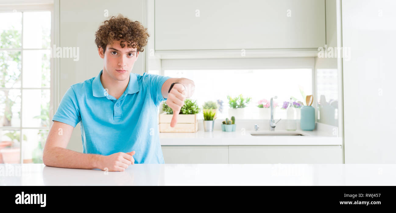 Wide shot of young handsome man at home looking unhappy and angry ...