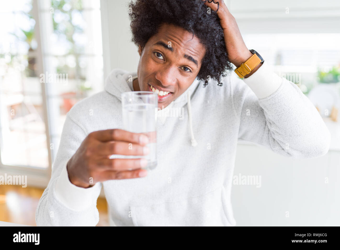 African American man drinking a glass of water at home stressed with ...