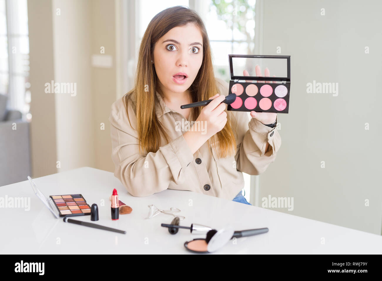 Beautiful young woman using make up cosmetics applying color from ...
