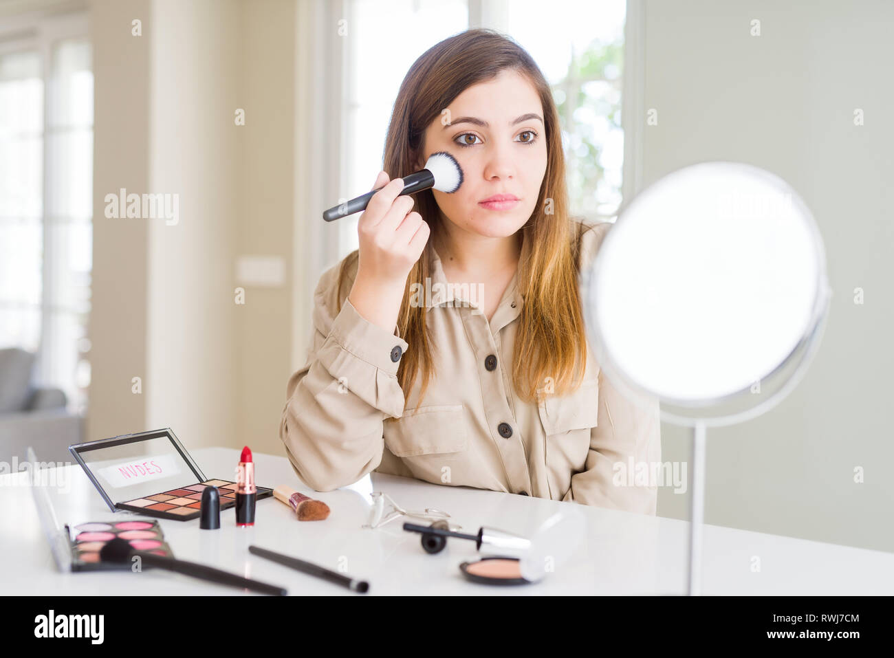Beautiful young woman using make up cosmetics applying color using ...