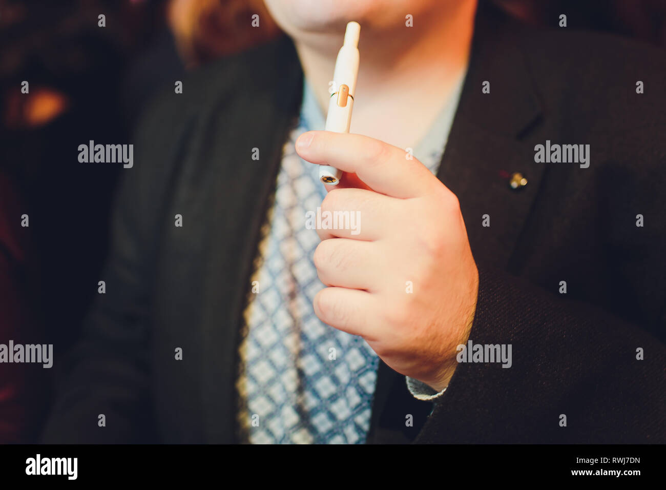 IQOS heat-not-burn tobacco product technology. Man holding e-cigarette ...