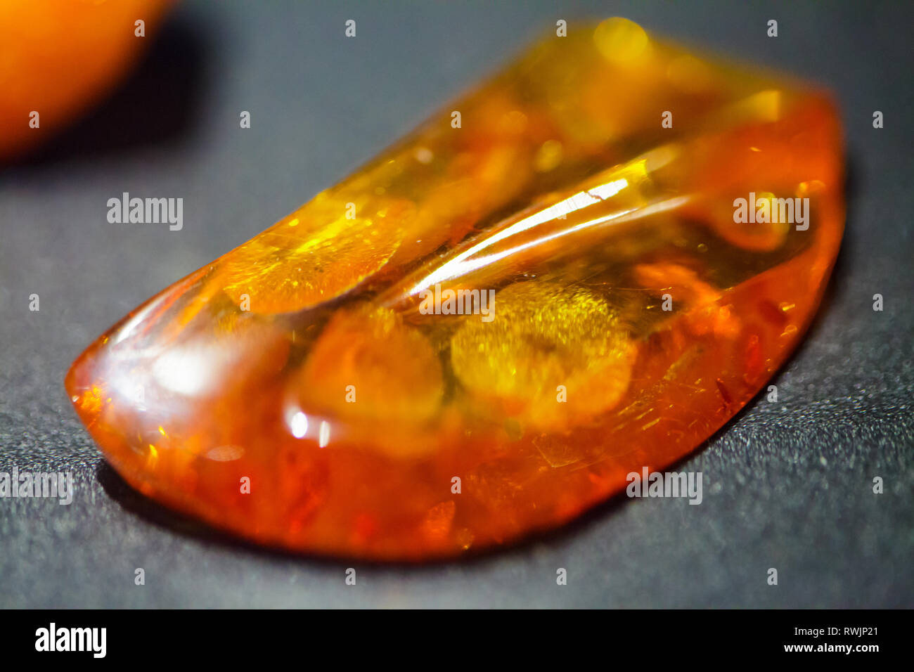 Macro. Closeup of amber golden mineral on grey gray background. Resin ...