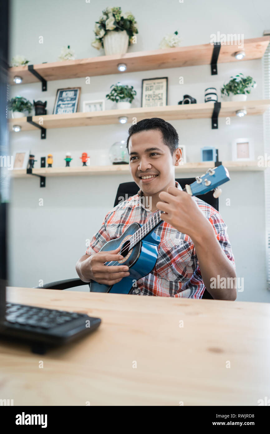 worker playing with his guitar while looking at his computer Stock ...
