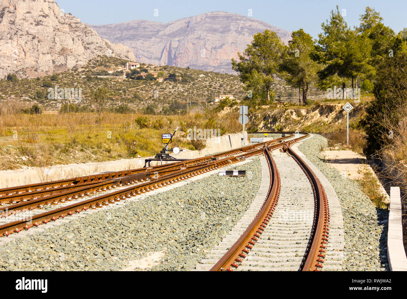 A railroad switch track with traffic signs, mountains and trees in the ...