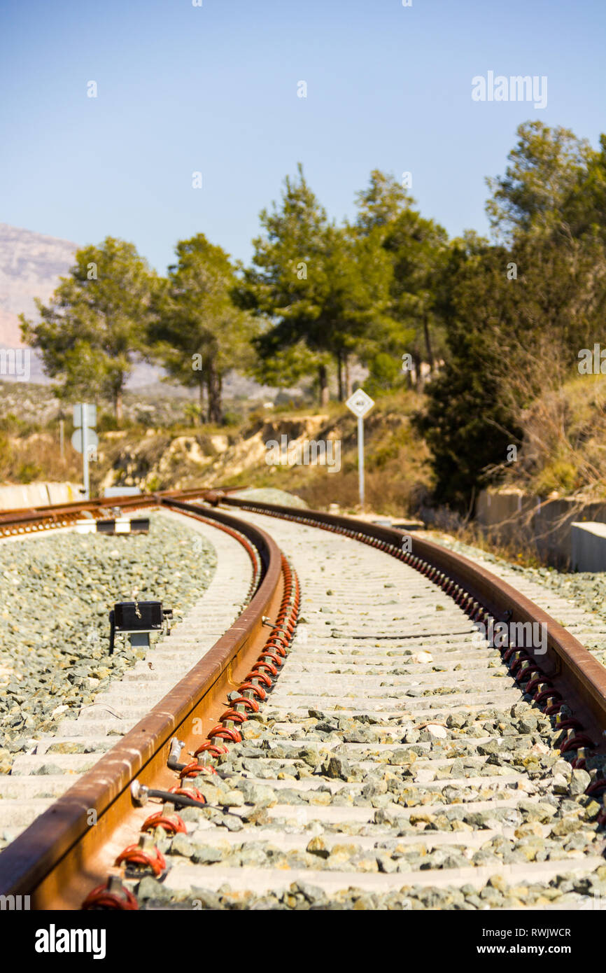 A railroad switch track with traffic signs, mountains and trees in the ...