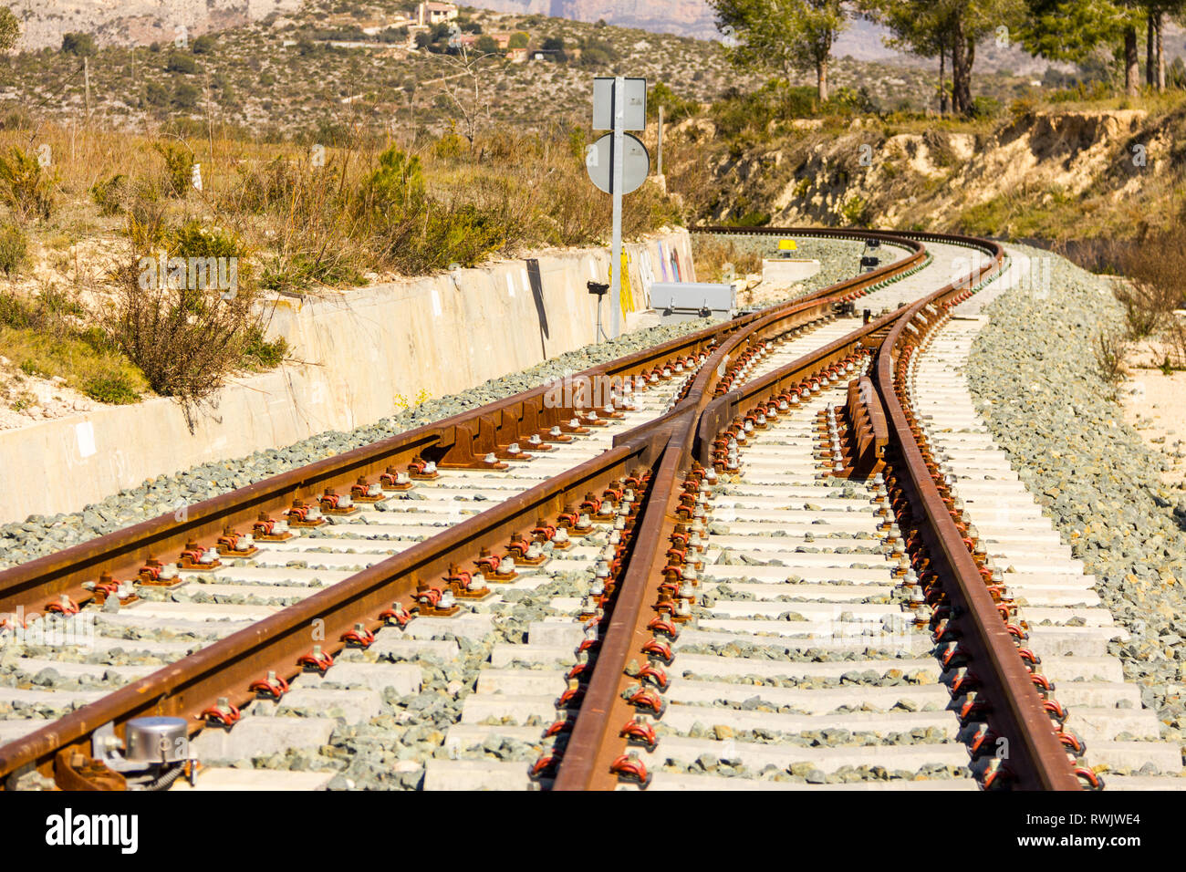 A railroad switch track with traffic signs, mountains and trees in the ...