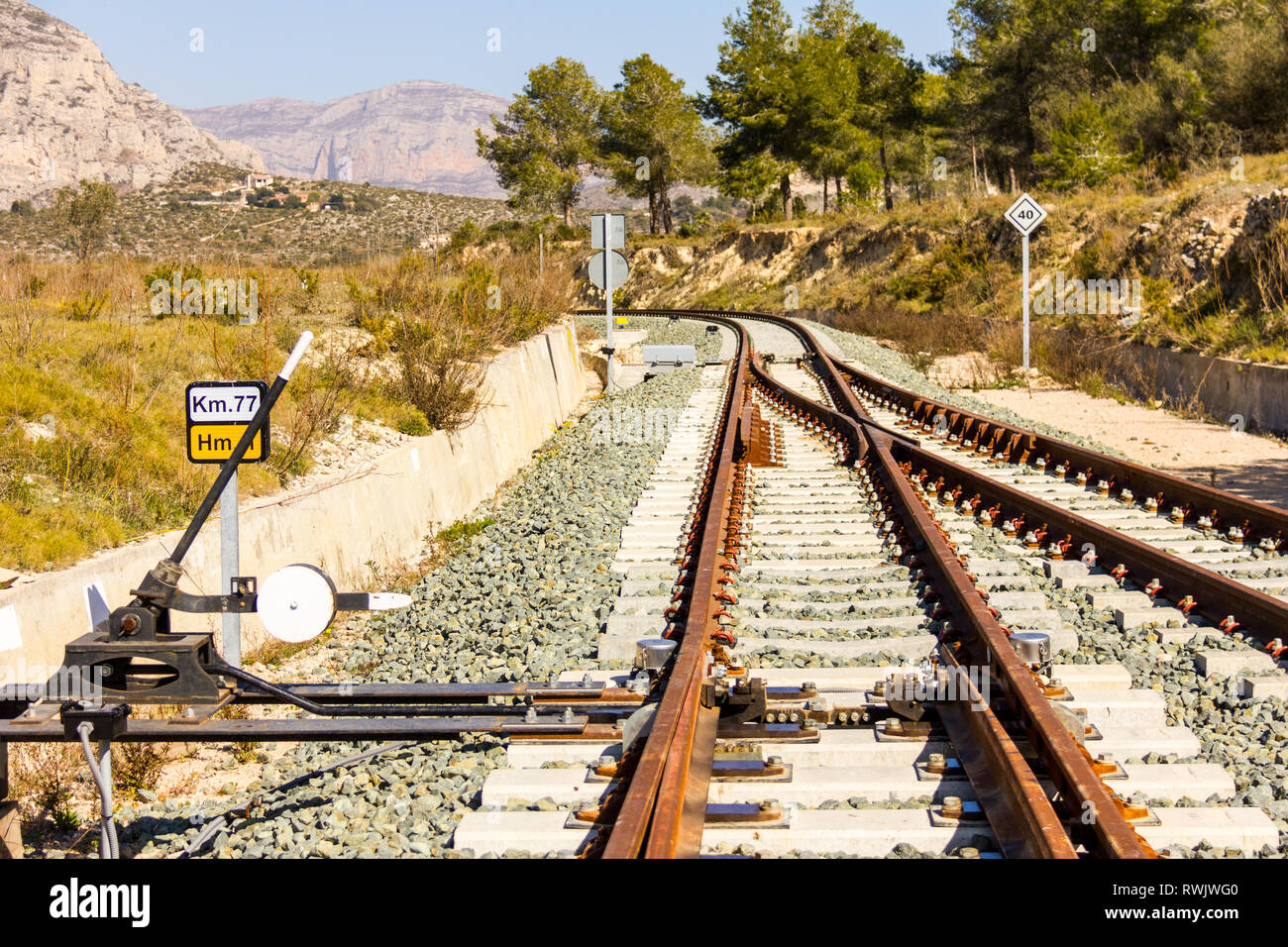 A railroad switch track with traffic signs, mountains and trees in the ...