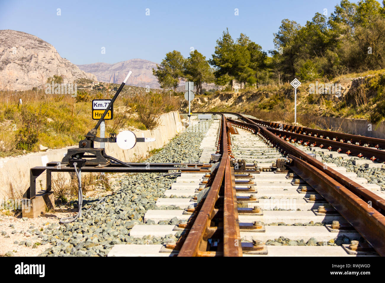A railroad switch track with traffic signs, mountains and trees in the ...