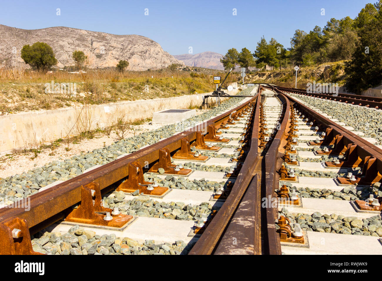 A railroad switch track with traffic signs, mountains and trees in the ...