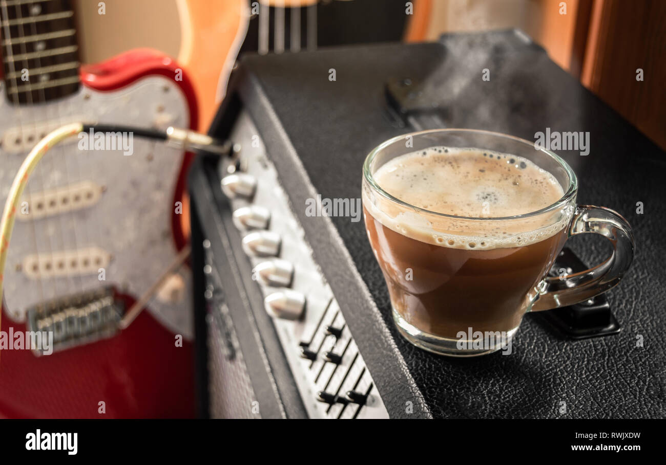 Delicious steaming coffee on guitar speaker with musical instruments in ...