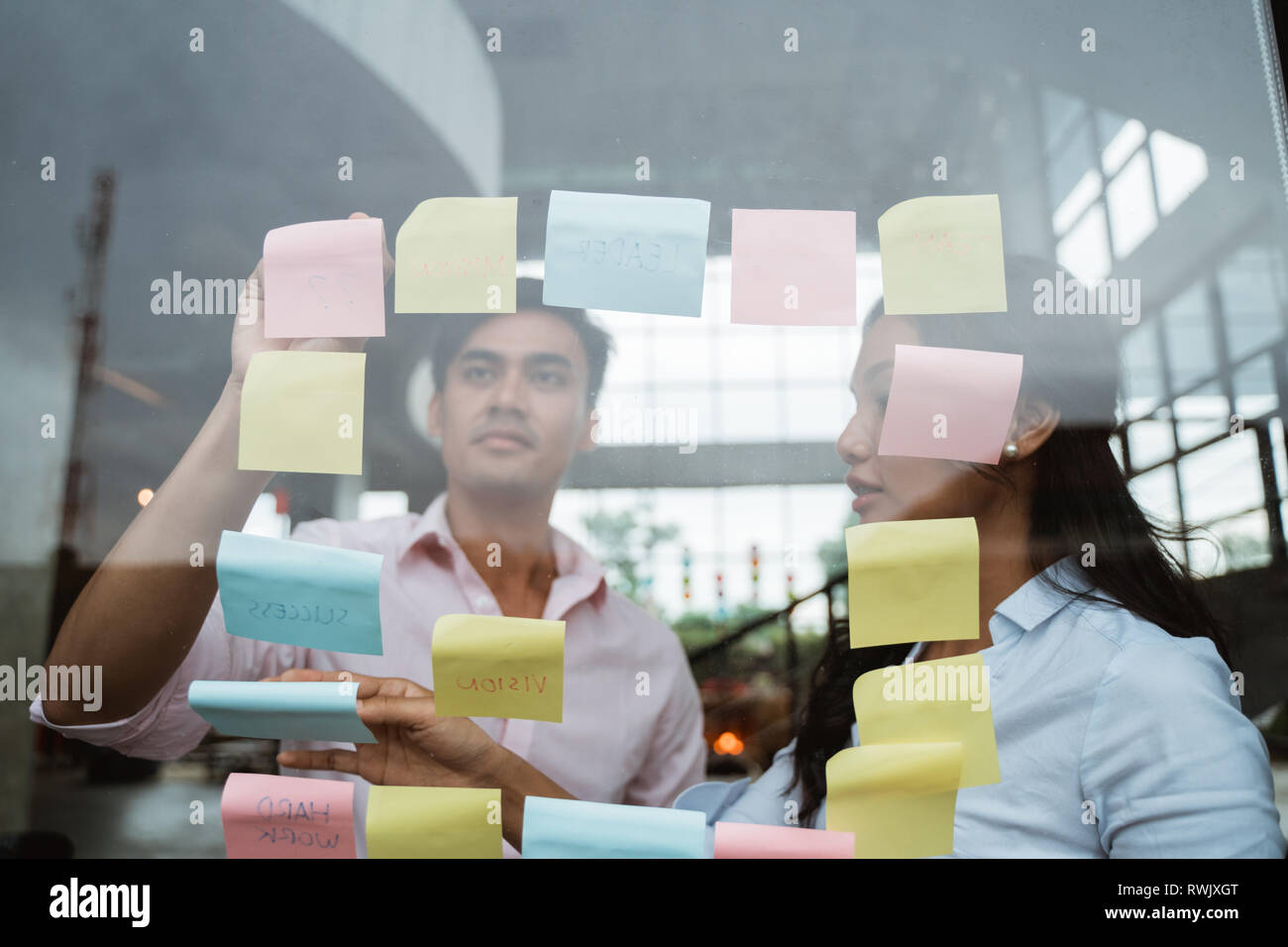 business partner brainstorming by sticking idea into the glass window ...