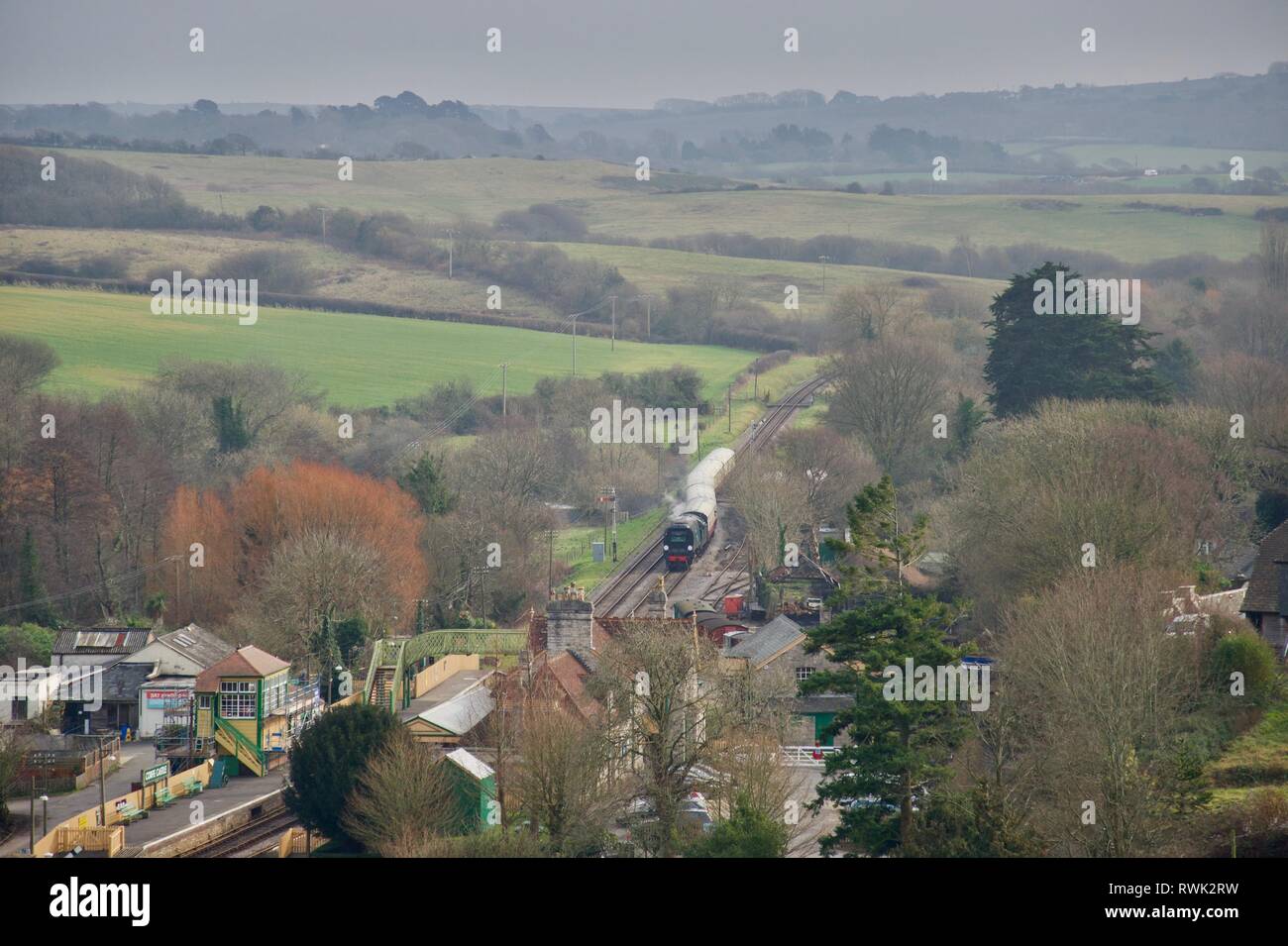 Steam train arriving at the old fashioned station in an ancient English ...