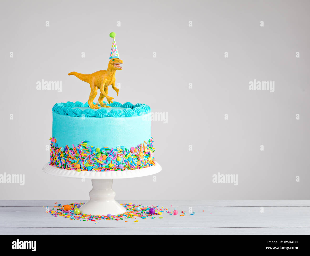 Blue buttercream birthday cake with colorful sprinkles and toy dinosaur ...