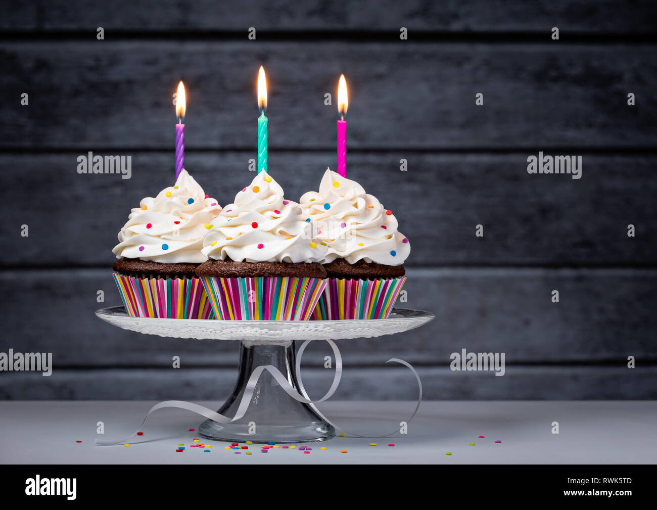 Three chocolate cupcakes with buttercream icing and Birthday candles on ...