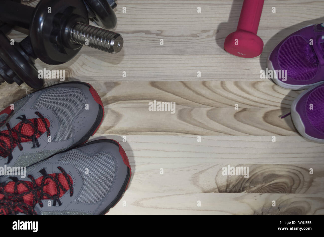 dumbbells and sport snickers on wooden background with space for text ...