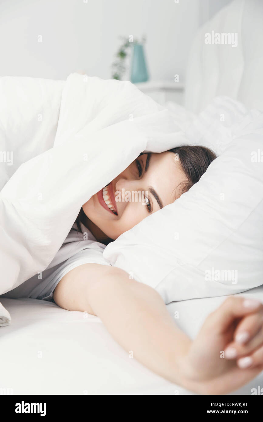 Cheerful smiling brunette woman waking up in her bed Stock Photo - Alamy