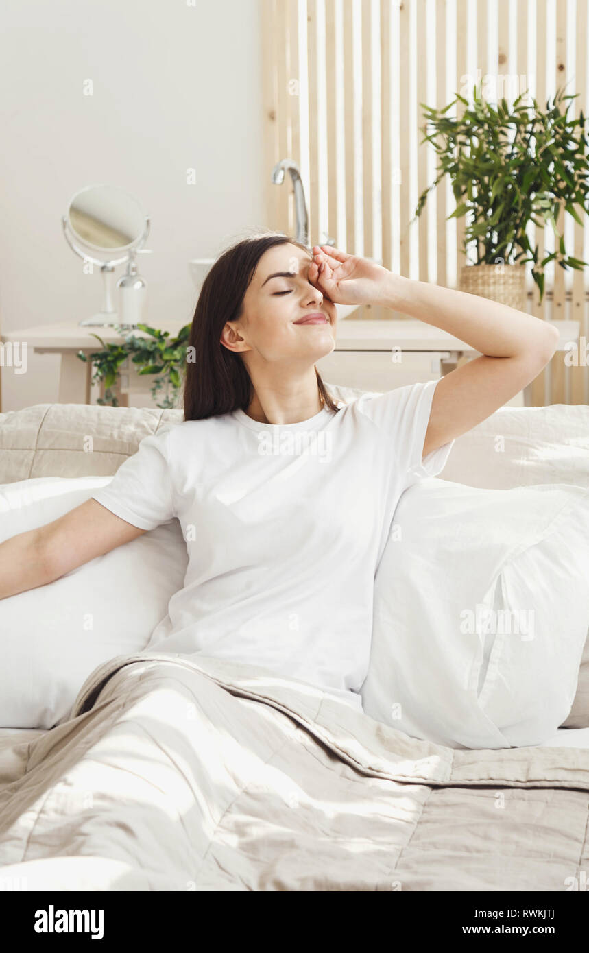 Beautiful woman waking up in her bed, she is smiling and stretching ...