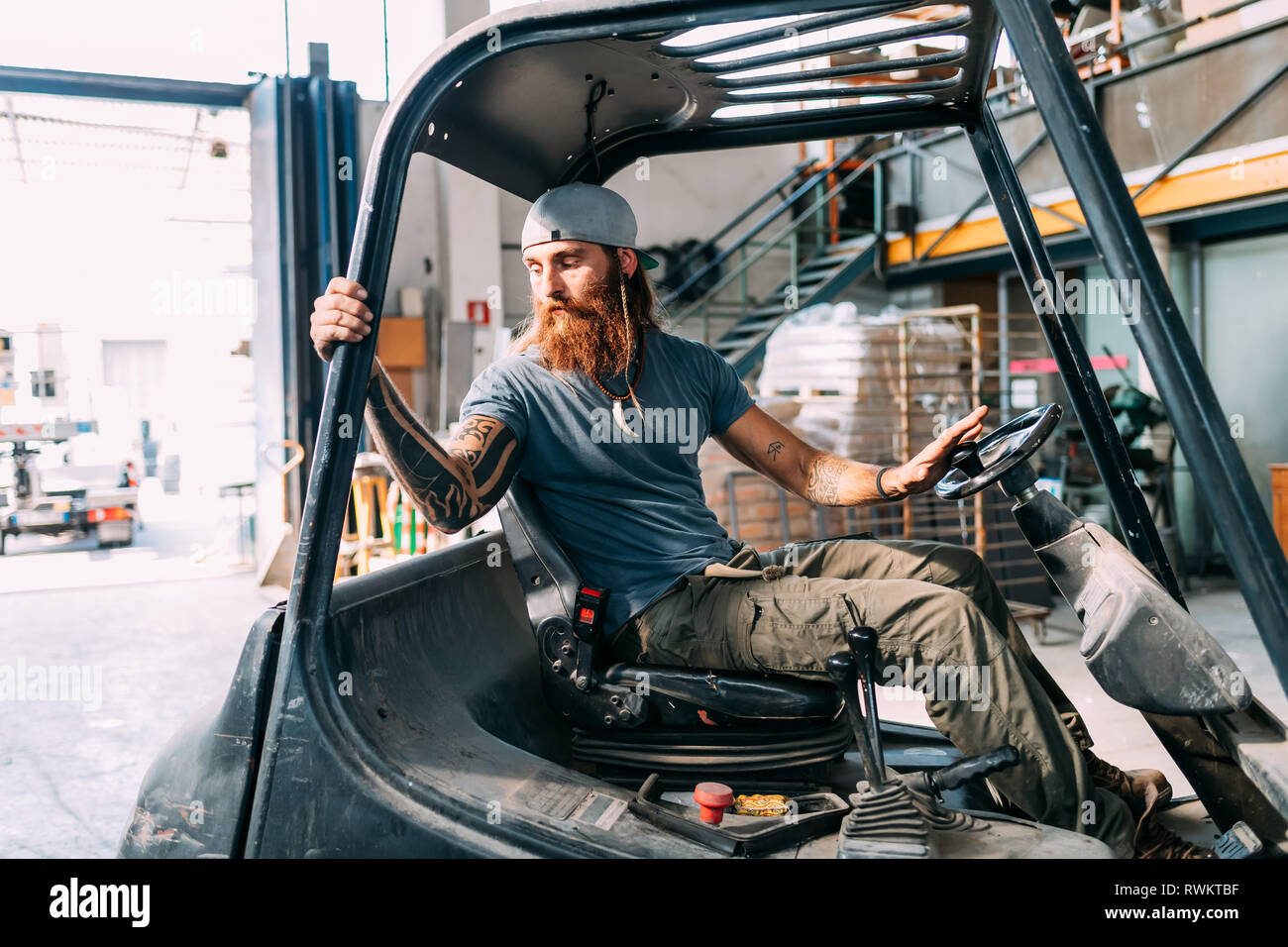 Man reversing fork lift out of warehouse Stock Photo - Alamy