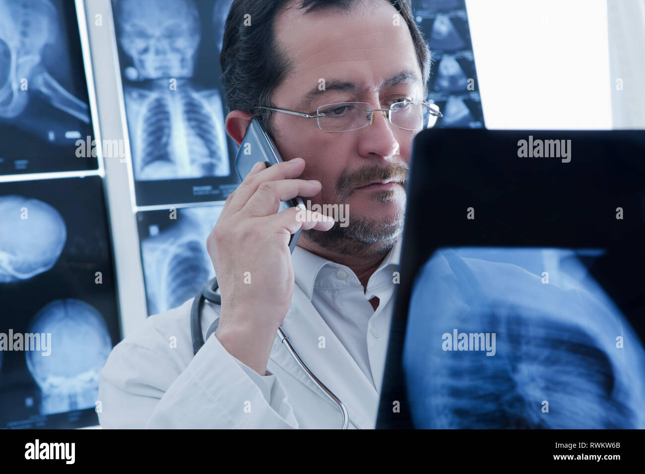 Doctor using smartphone and examining Xray image Stock Photo - Alamy