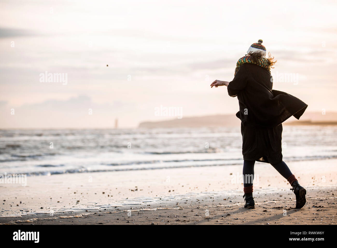Woman throwing pebbles on beach Stock Photo - Alamy