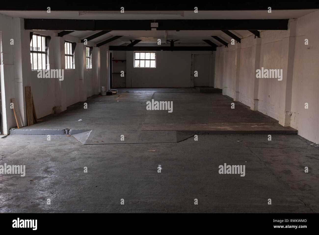 The inside of an empty long farm building with white walls and black ...