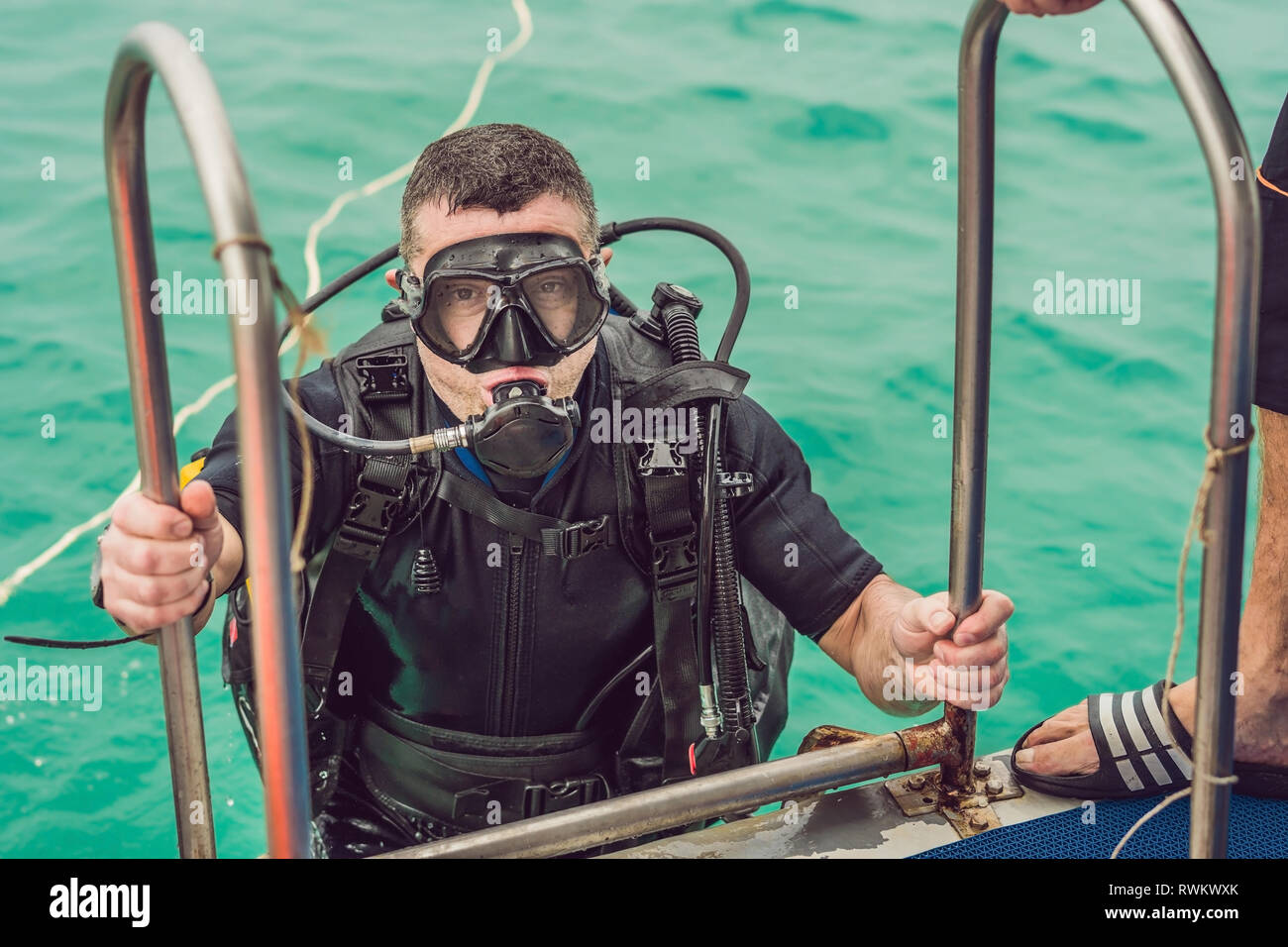Happy diver returns to the ship after diving Stock Photo - Alamy