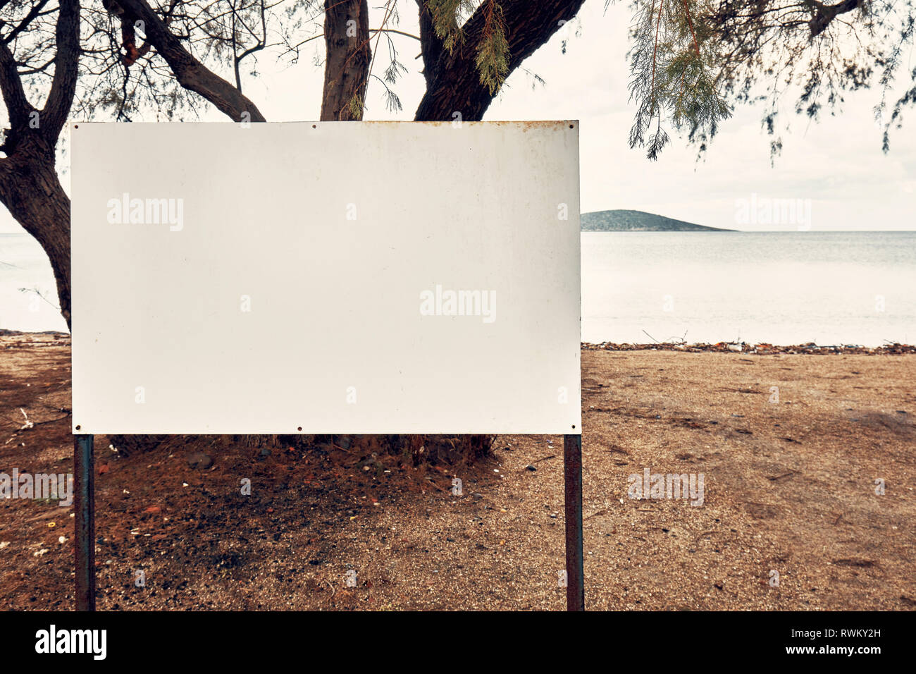 Blank empty white sign post on the beach near the sea on a seaside ...