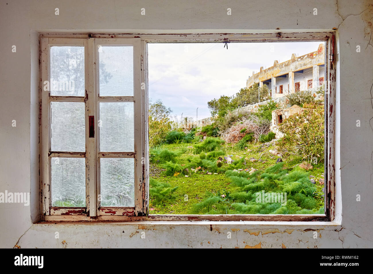 Interior of a ruined house with a broken window frame looking through a ...