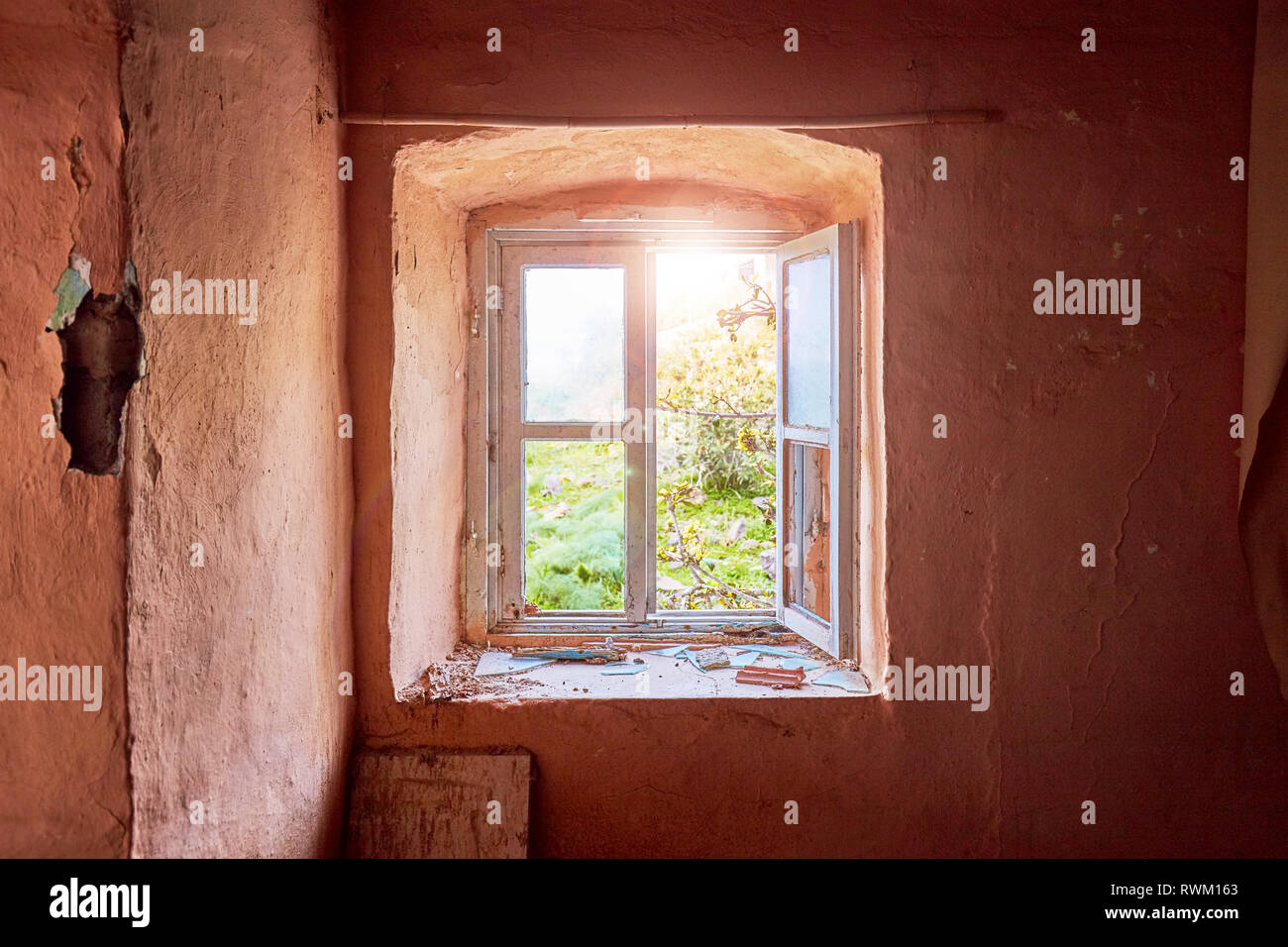 Interior of a ruined old cottage with a light pink wall and a broken ...