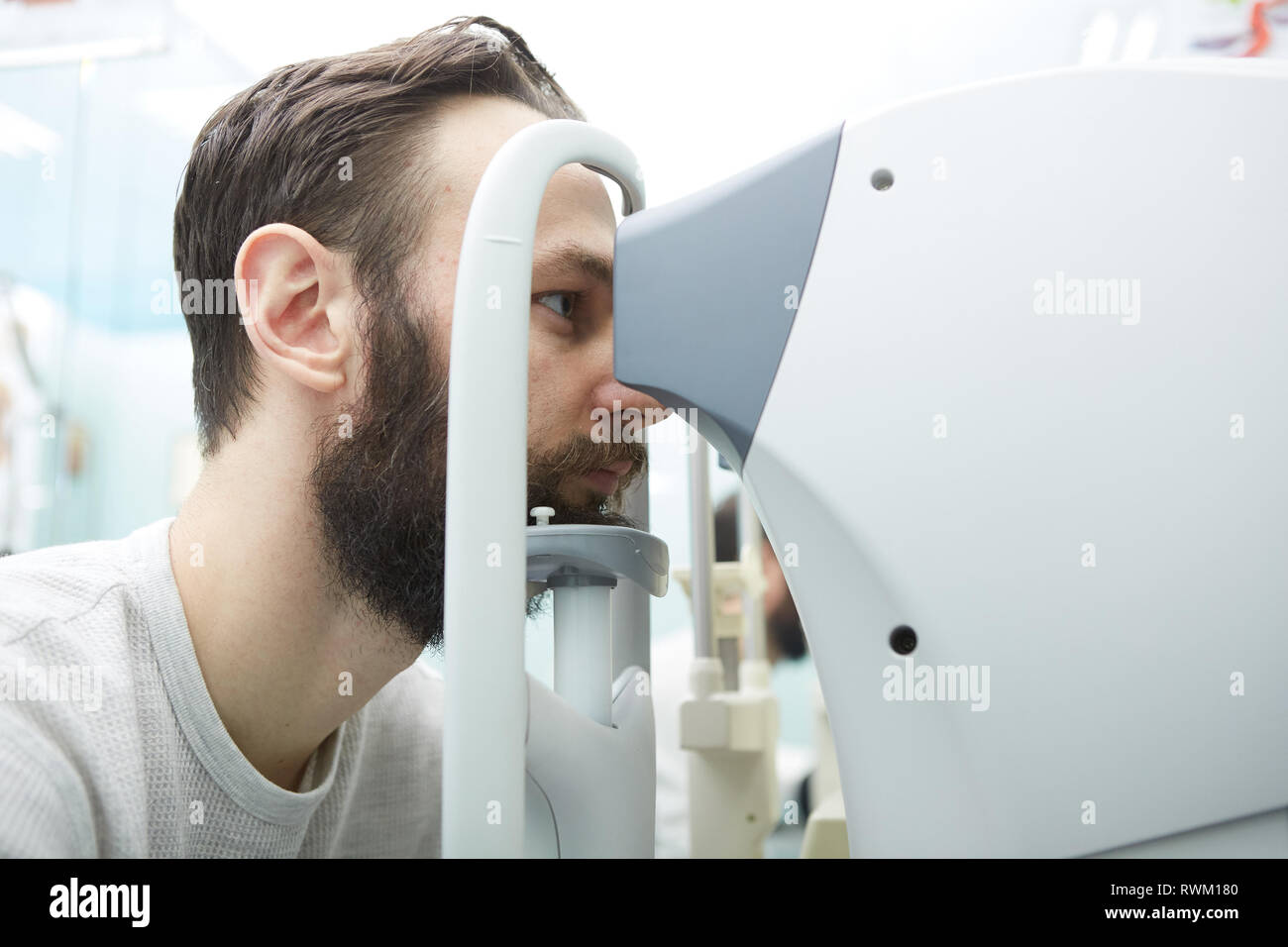 Handsome young man is checking the eye vision in modern ophthalmology ...