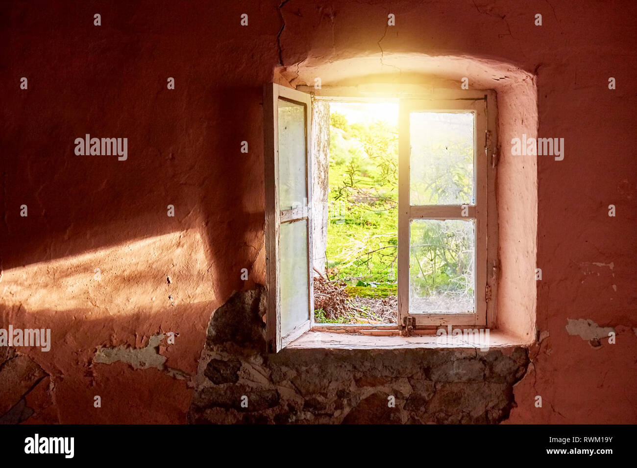 Interior of a ruined old cottage with a light pink wall and a broken ...
