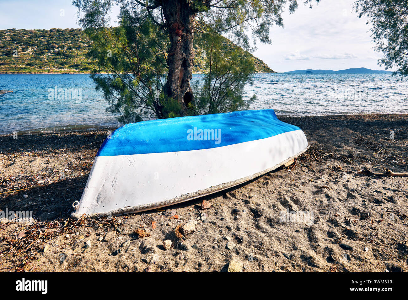 White blue vintage rustic wooden boat inverted on a sandy beach in ...